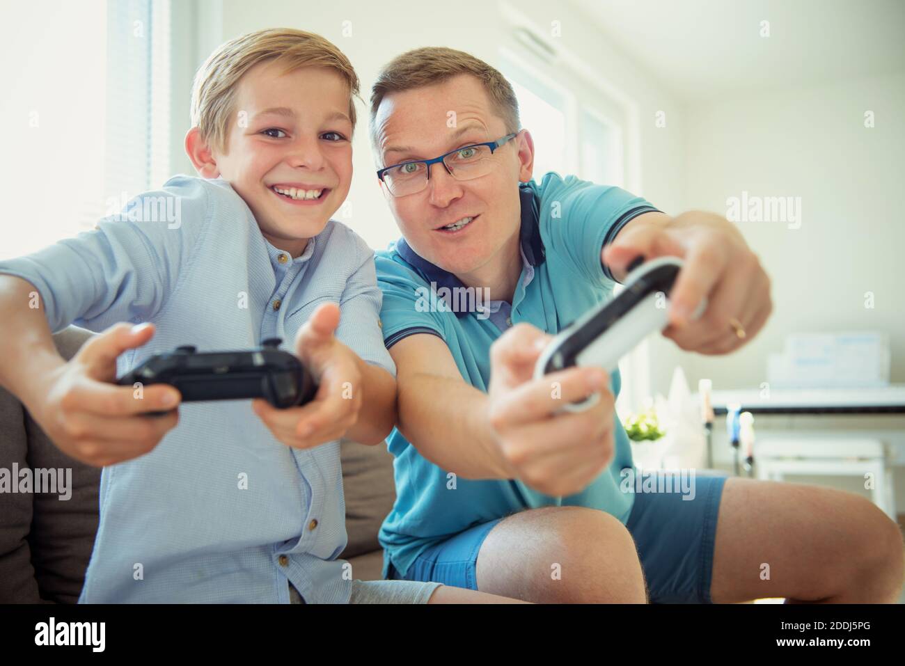 Happy young father and his son playing computer games with controllers ...