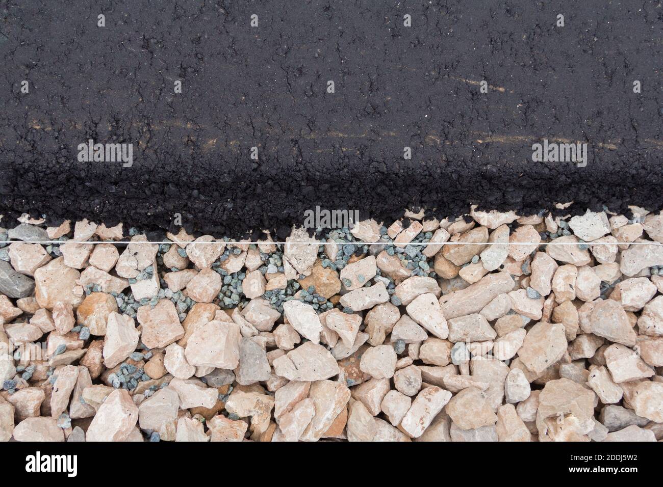 Stones on the edge of the asphalt road The border of the asphalt road ...