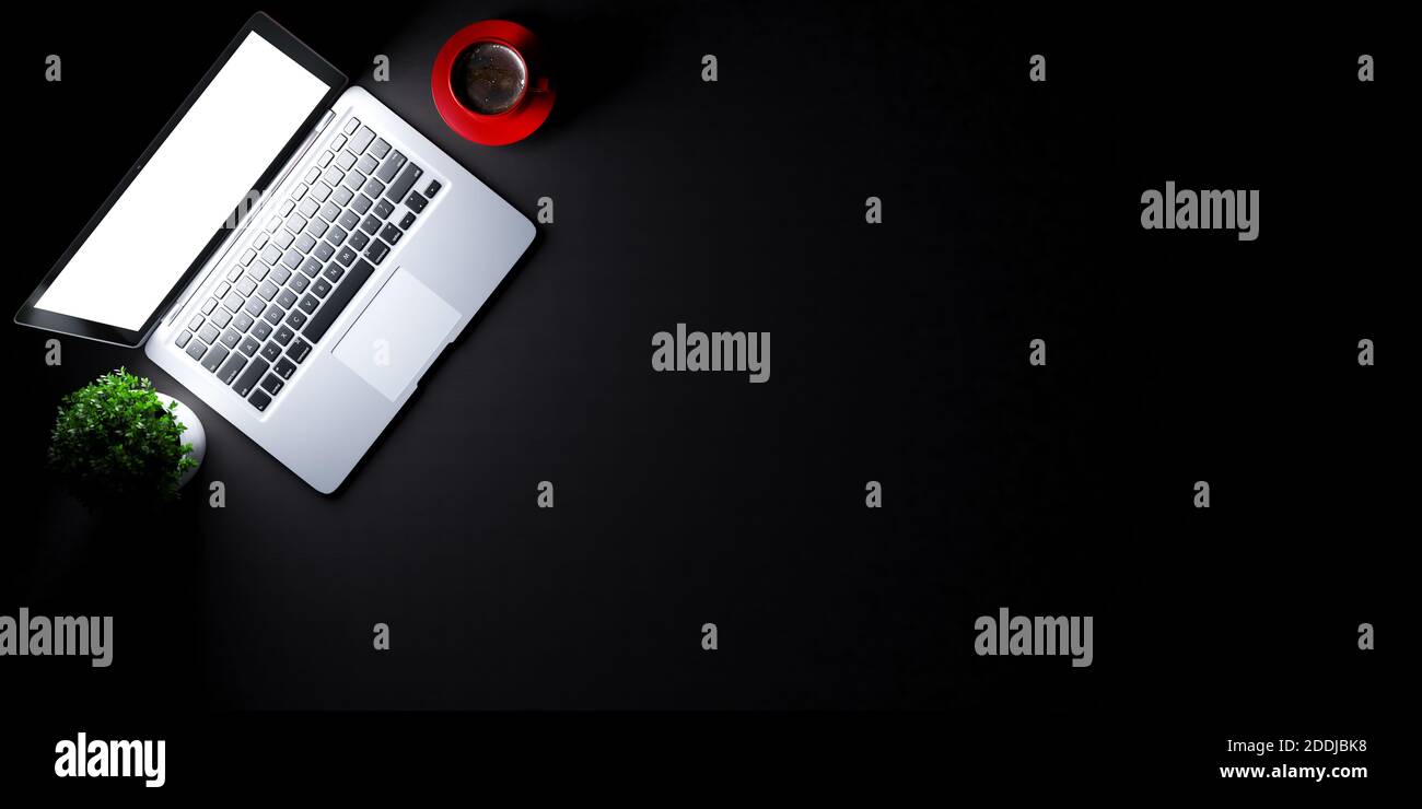 Top view of laptop concept with black desk under spot light and red ...