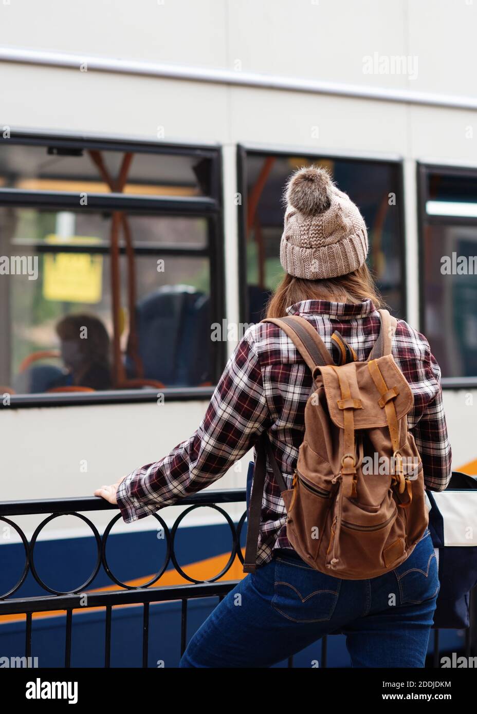 woman in a shirt with backpack waiting for a bus on bus stop Stock ...