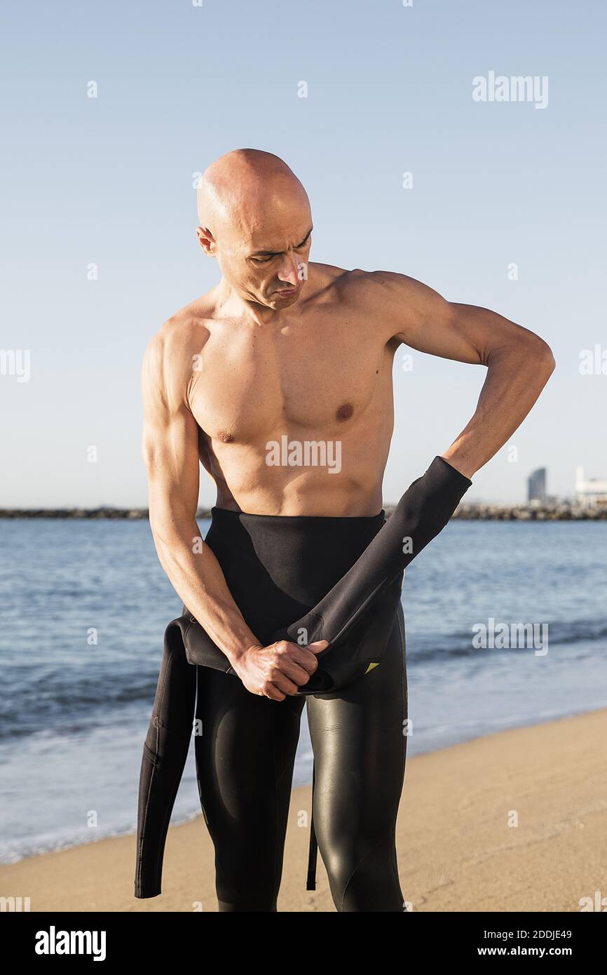 A vertical shot of of a male Caucasian athletic swimmer taking off his ...