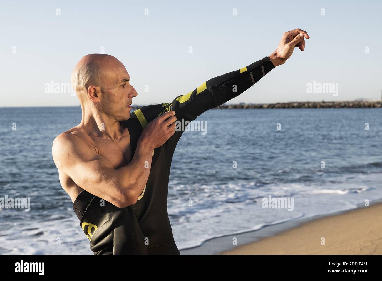 A shallow focus of a male Caucasian athletic swimmer putting on his ...