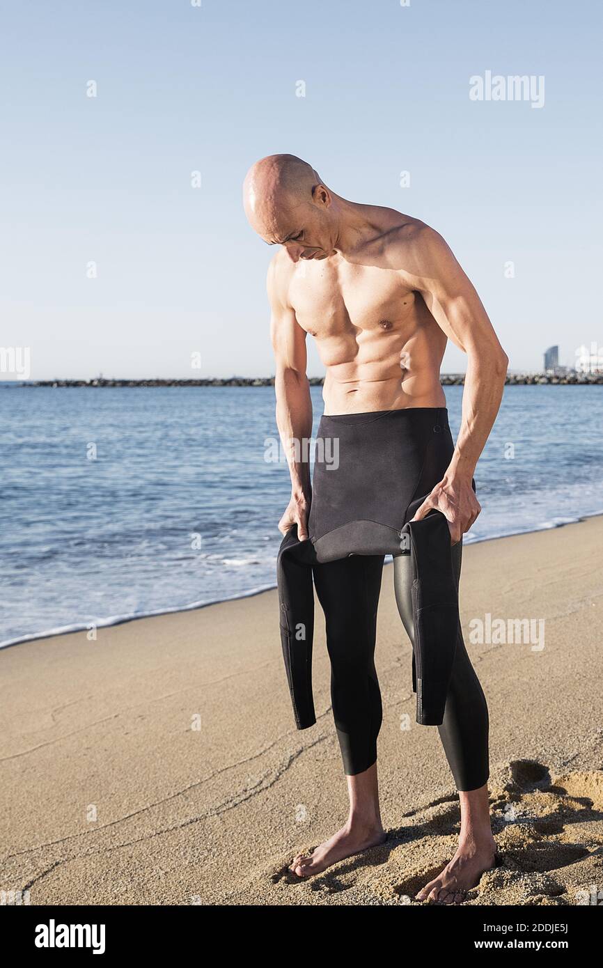 A vertical shot of of a male Caucasian athletic swimmer taking off his ...