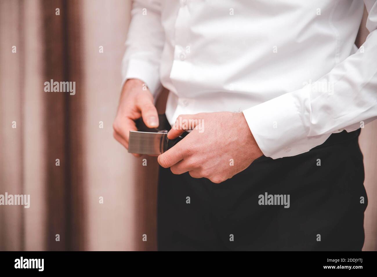a male person with a white shirt wearing his belt Stock Photo - Alamy