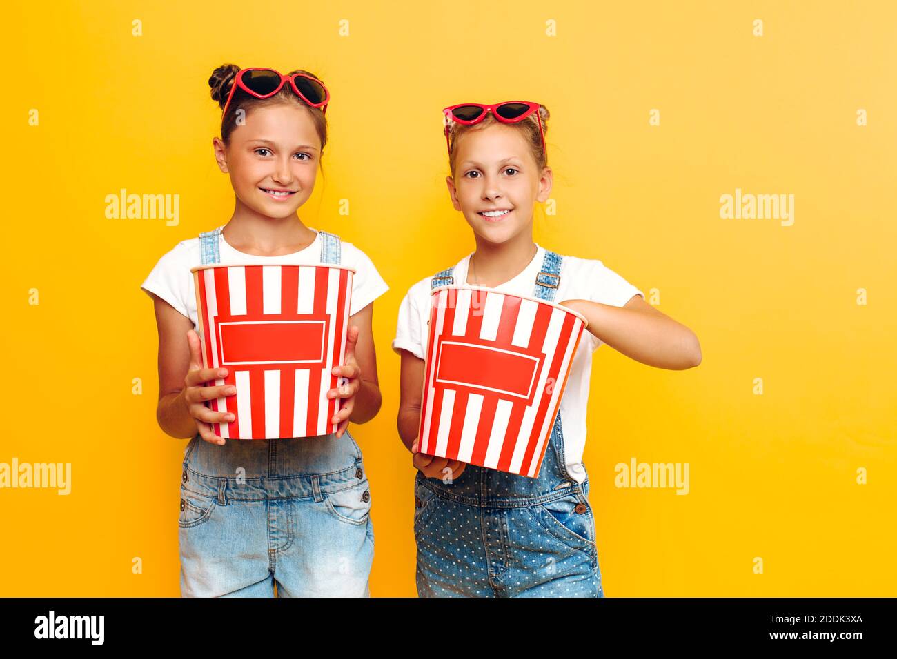 Two teenage girls, stylish girlfriends with popcorn in their hands ...
