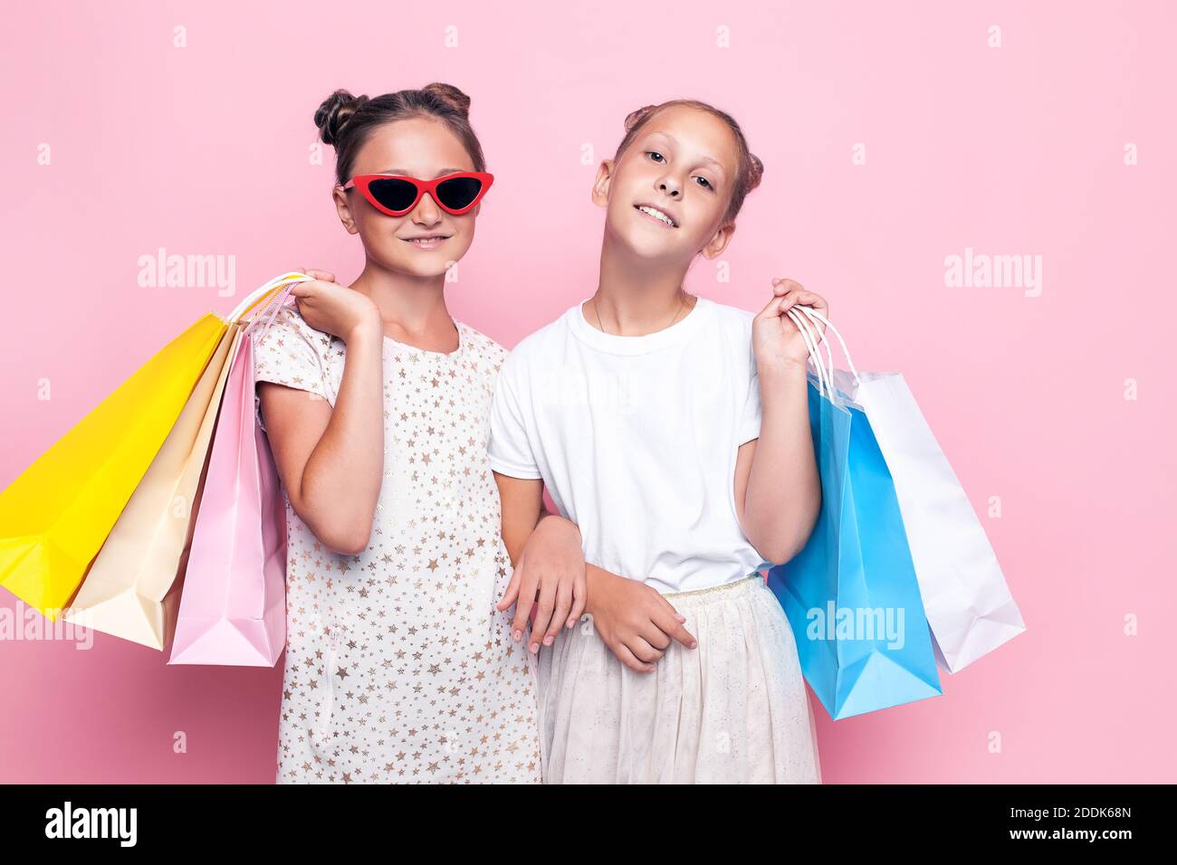 Two smiling teenage girls hold bags in their hands after a shopping ...