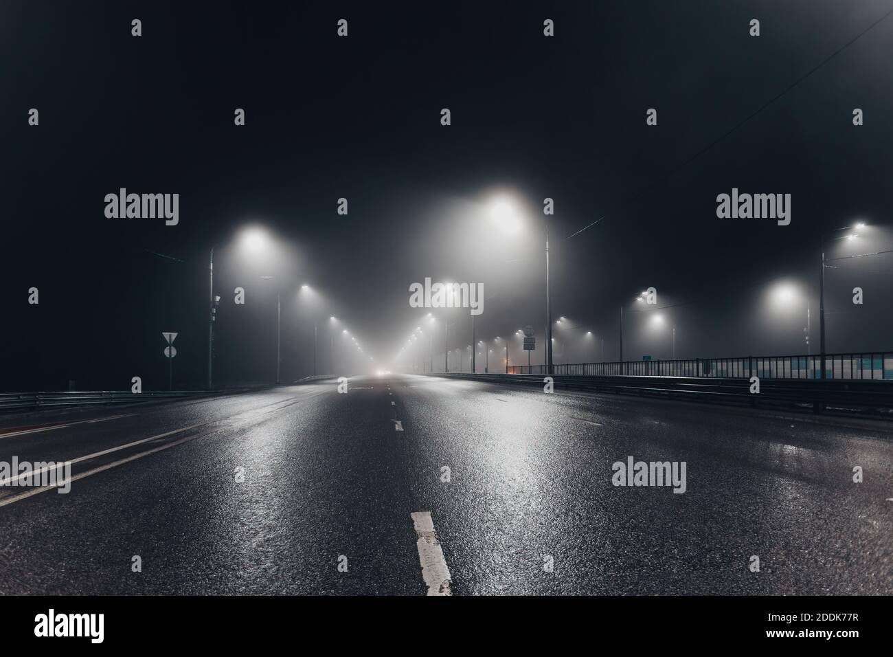 Foggy misty night road illuminated by street lights Stock Photo - Alamy