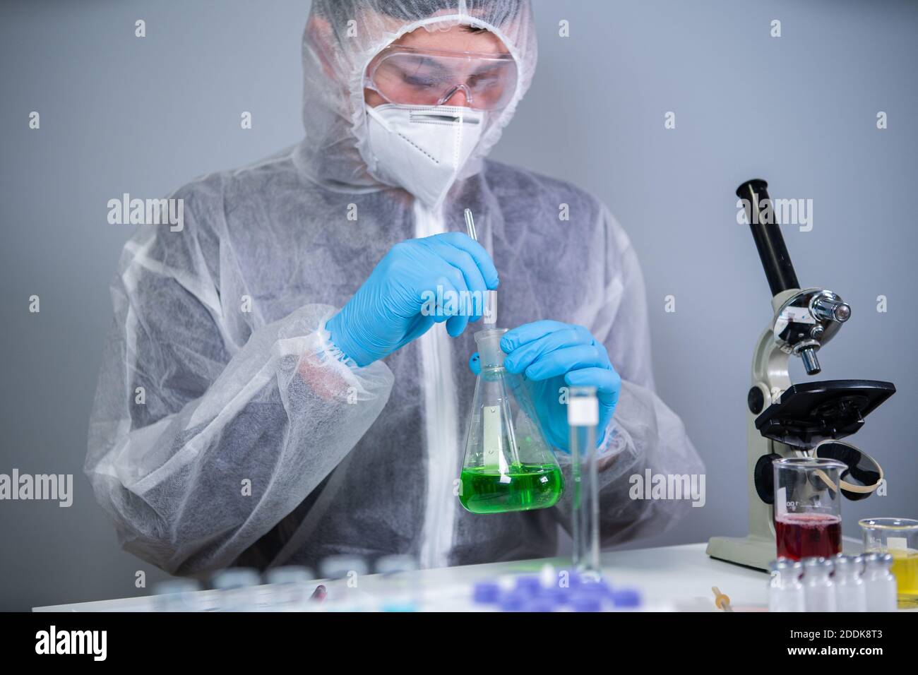Scientist shaking green fluid in beaker. Young laboratory assistant ...