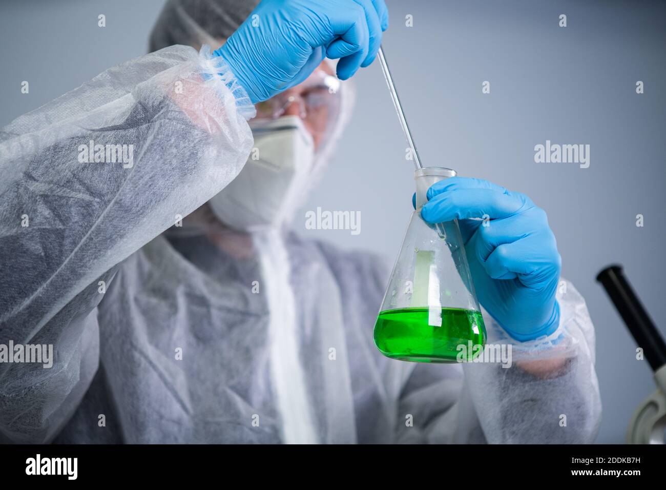Scientist shaking green fluid in beaker. Young laboratory assistant ...