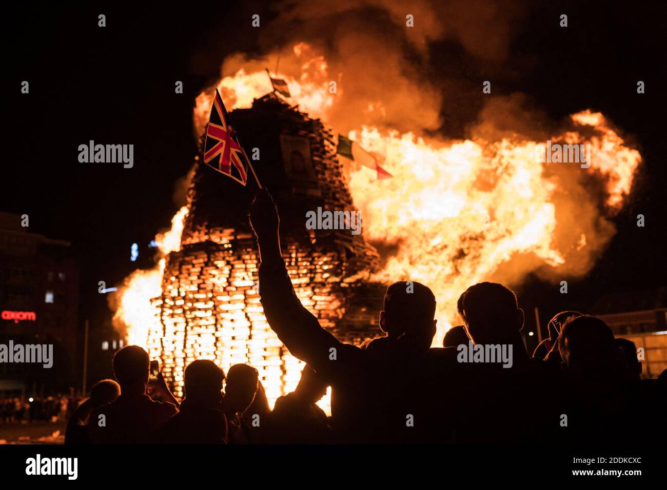 A man waves a Union Jack flag in front of the burning bonfire set on ...