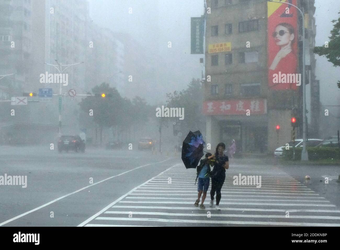 People struggle with heavy winds and rain while crossing the street as ...