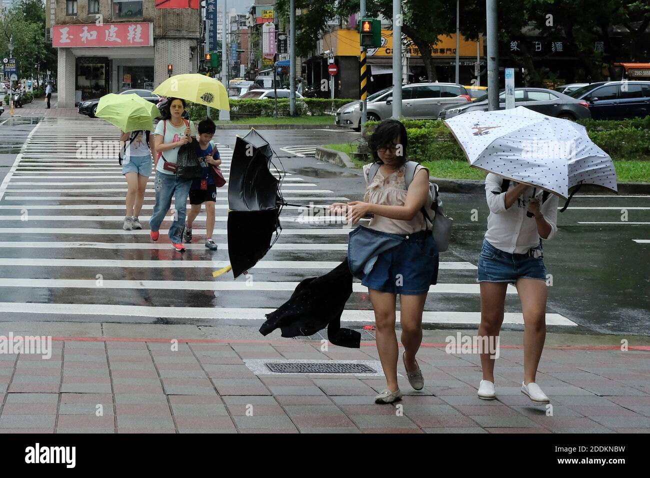 People struggle with heavy winds and rain while crossing the street as ...