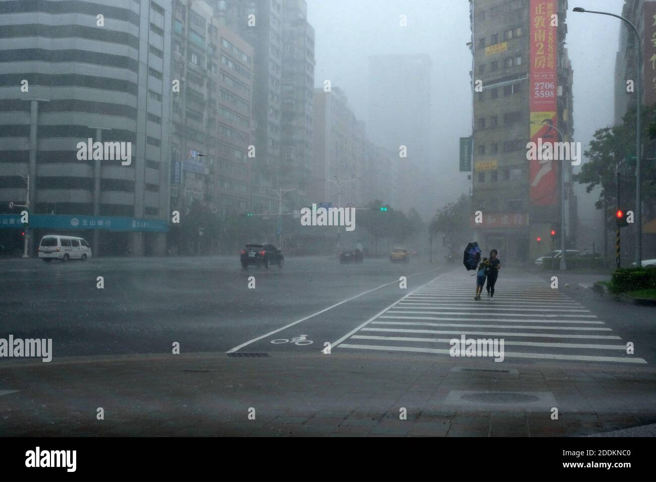 People struggle with heavy winds and rain while crossing the street as ...