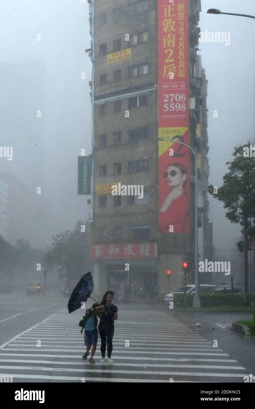 People struggle with heavy winds and rain while crossing the street as ...