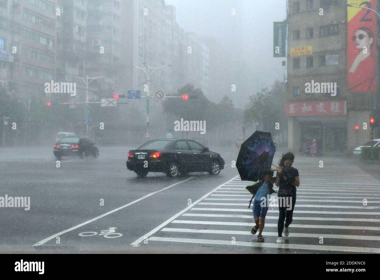 People struggle with heavy winds and rain while crossing the street as ...