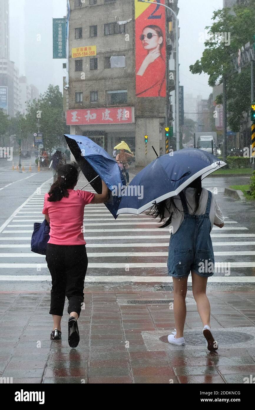 People struggle with heavy winds and rain while crossing the street as ...