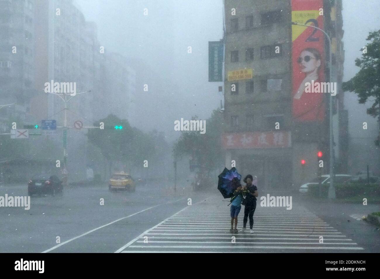 People struggle with heavy winds and rain while crossing the street as ...