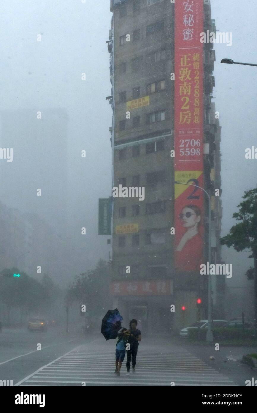 People struggle with heavy winds and rain while crossing the street as ...