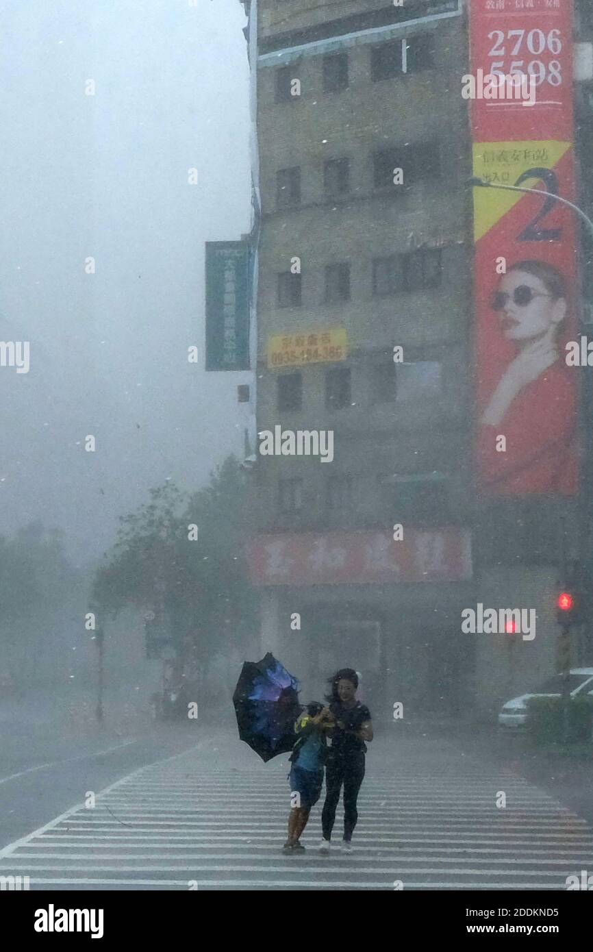 People struggle with heavy winds and rain while crossing the street as ...