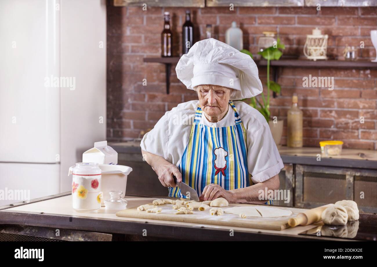 Senior woman in chef hat preparing pastries in kitchen at home Stock ...