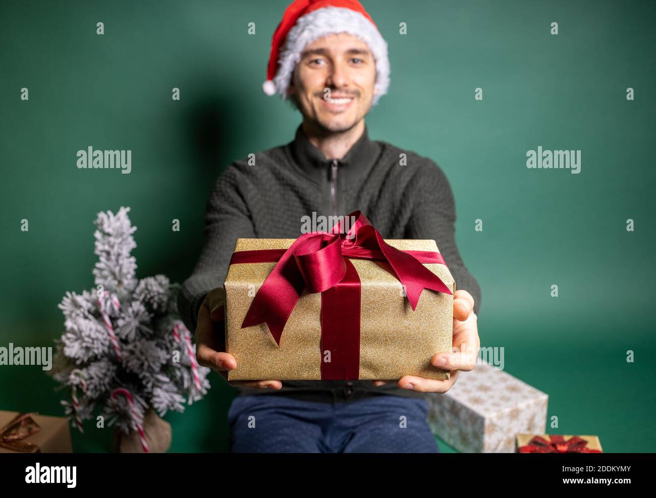 man with many wrapped gifts on green background Stock Photo - Alamy