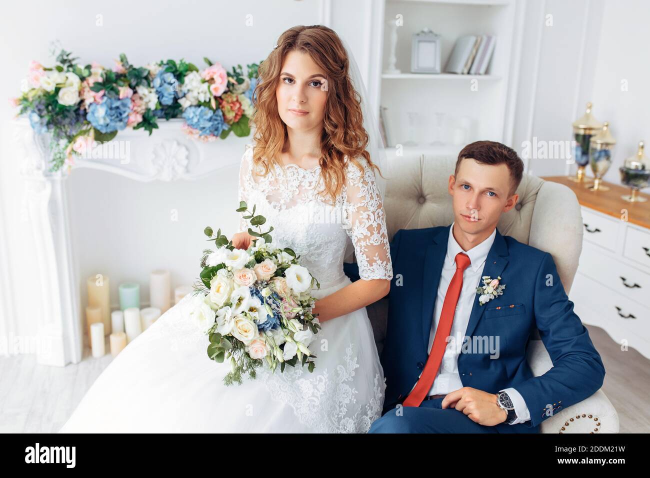 Beautiful bride in white dress and groom in suit, posing in white ...