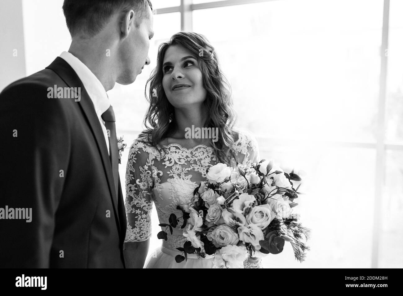 Beautiful bride in white dress and groom in suit, posing in white ...