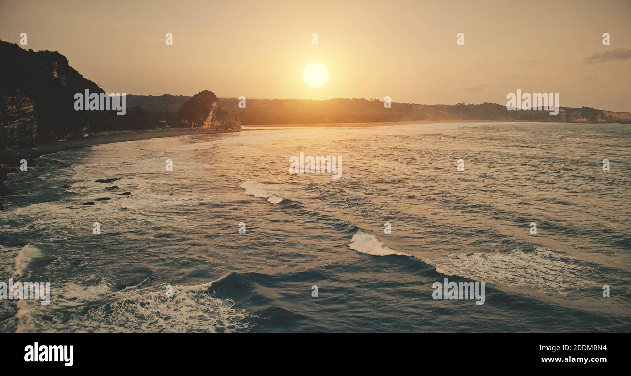 Rock ocean shore sunset with waves at water surface in aerial view ...