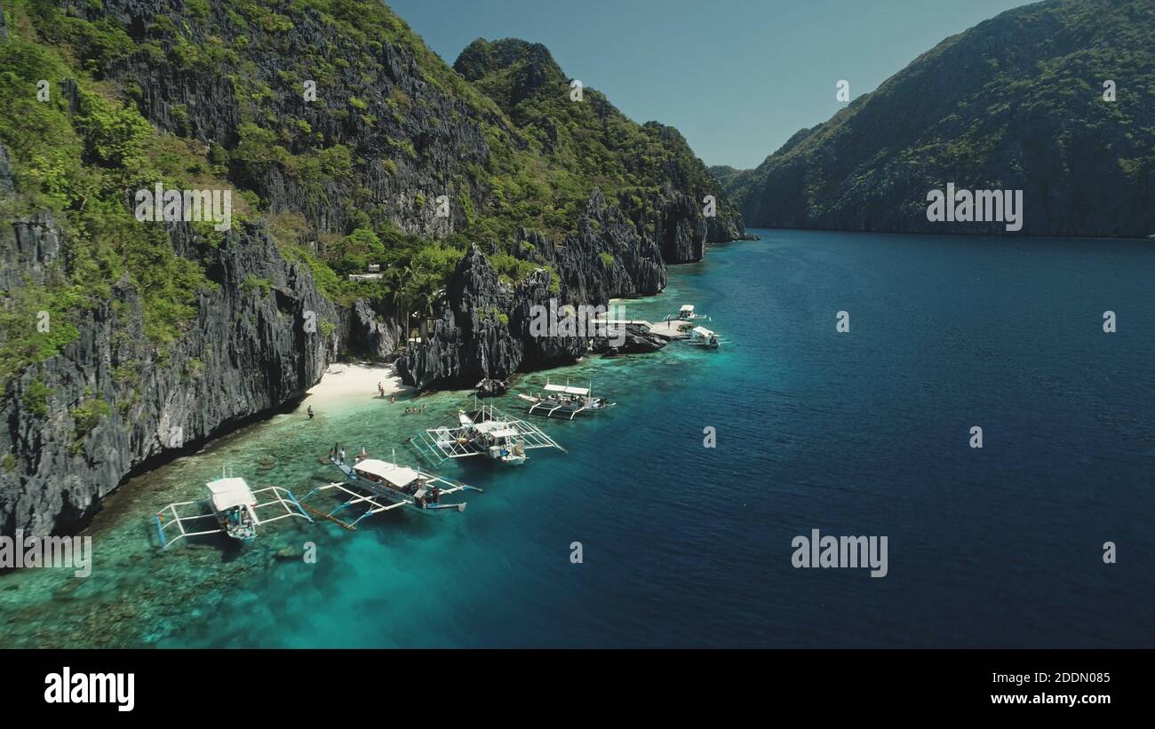 Closeup aerial view of boats at ocean cliff coast with green tropical ...