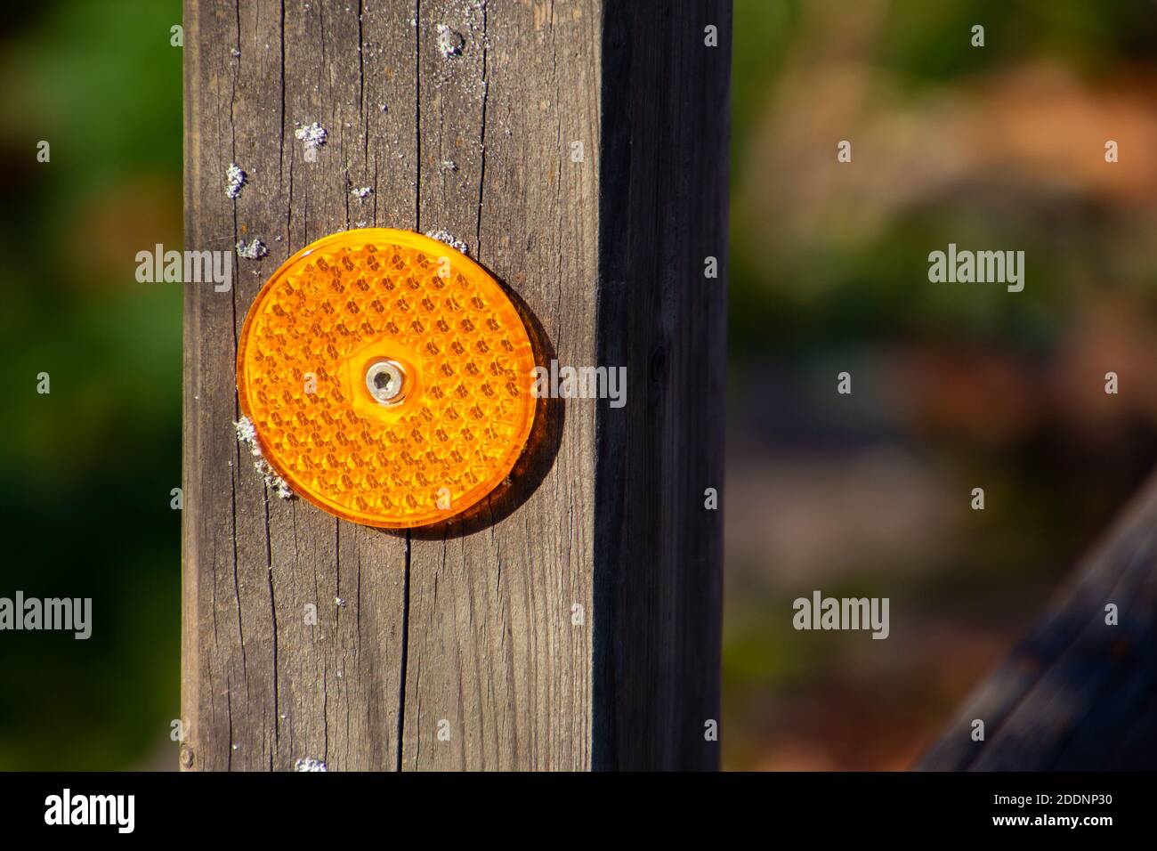 Round bright orange plastic reflector on a wooden post Stock Photo - Alamy