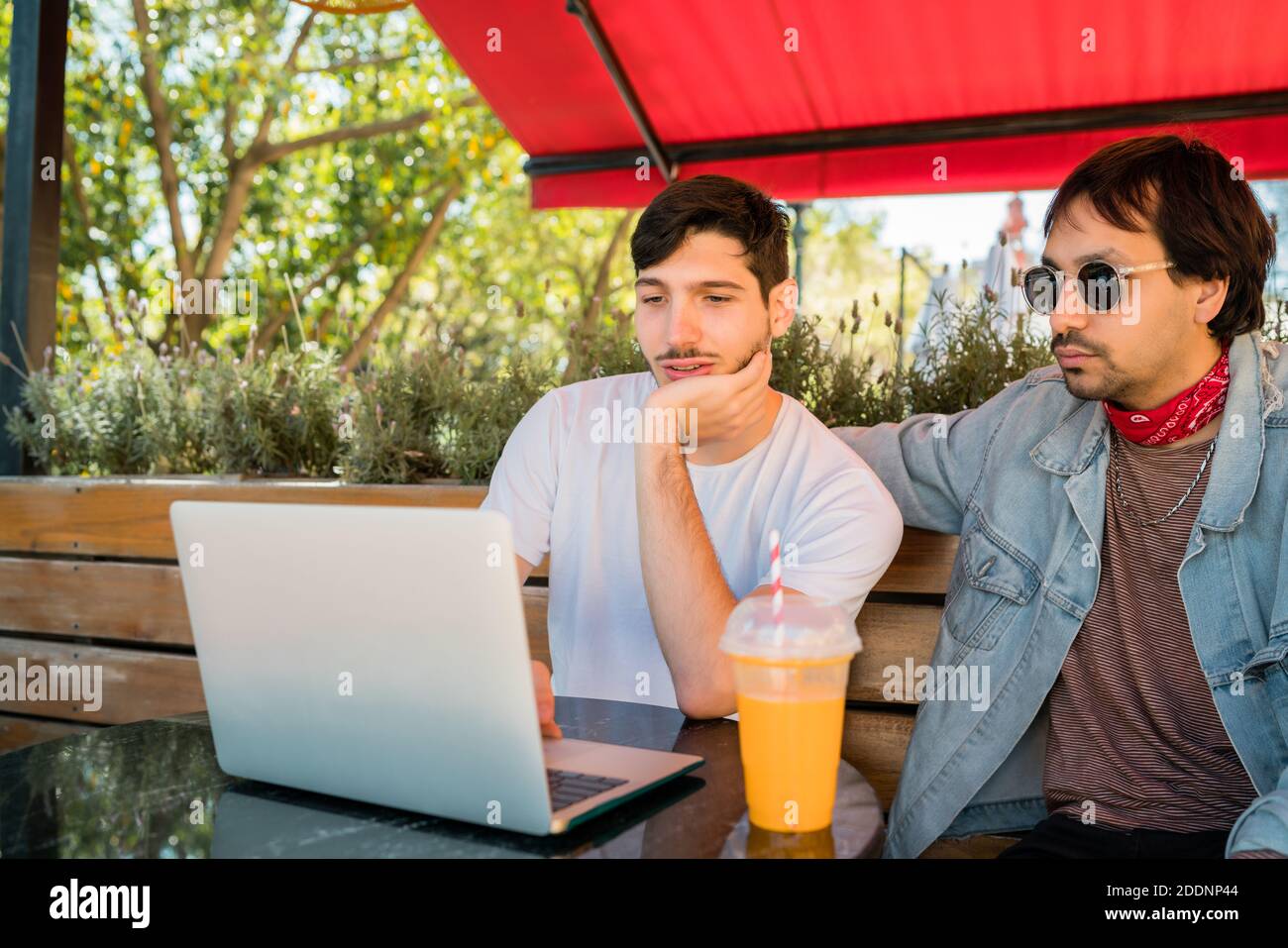 Two young friends using laptop at coffee shop Stock Photo - Alamy