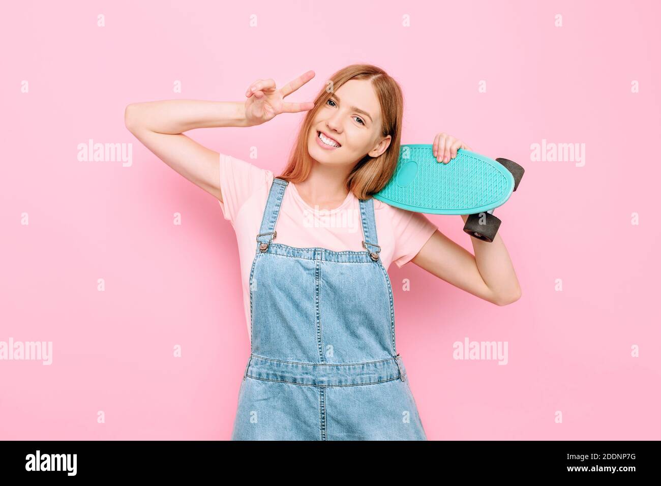 Portrait Of An Attractive Skater Girl Holding A Skateboard And Showing