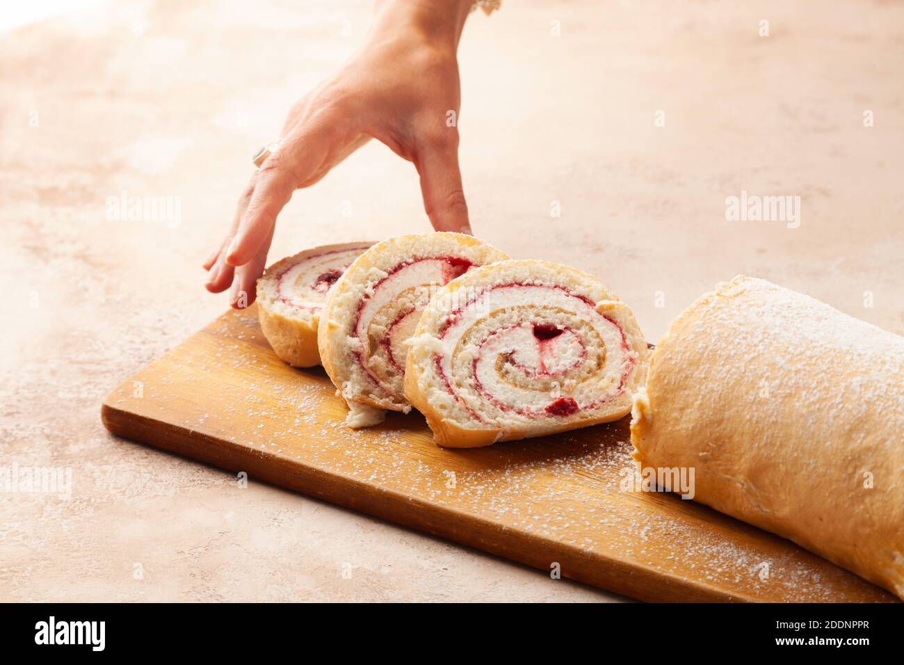Baked biscuit swiss roll dessert with fruits and cream chopped on ...