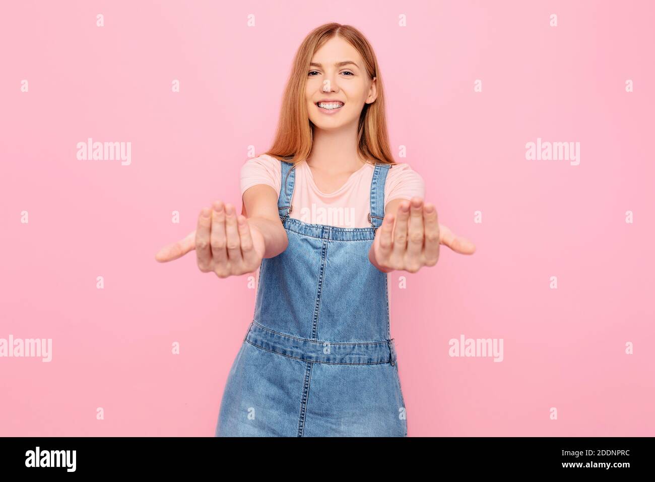 A happy smiling young girl makes a greeting or presentation gesture ...