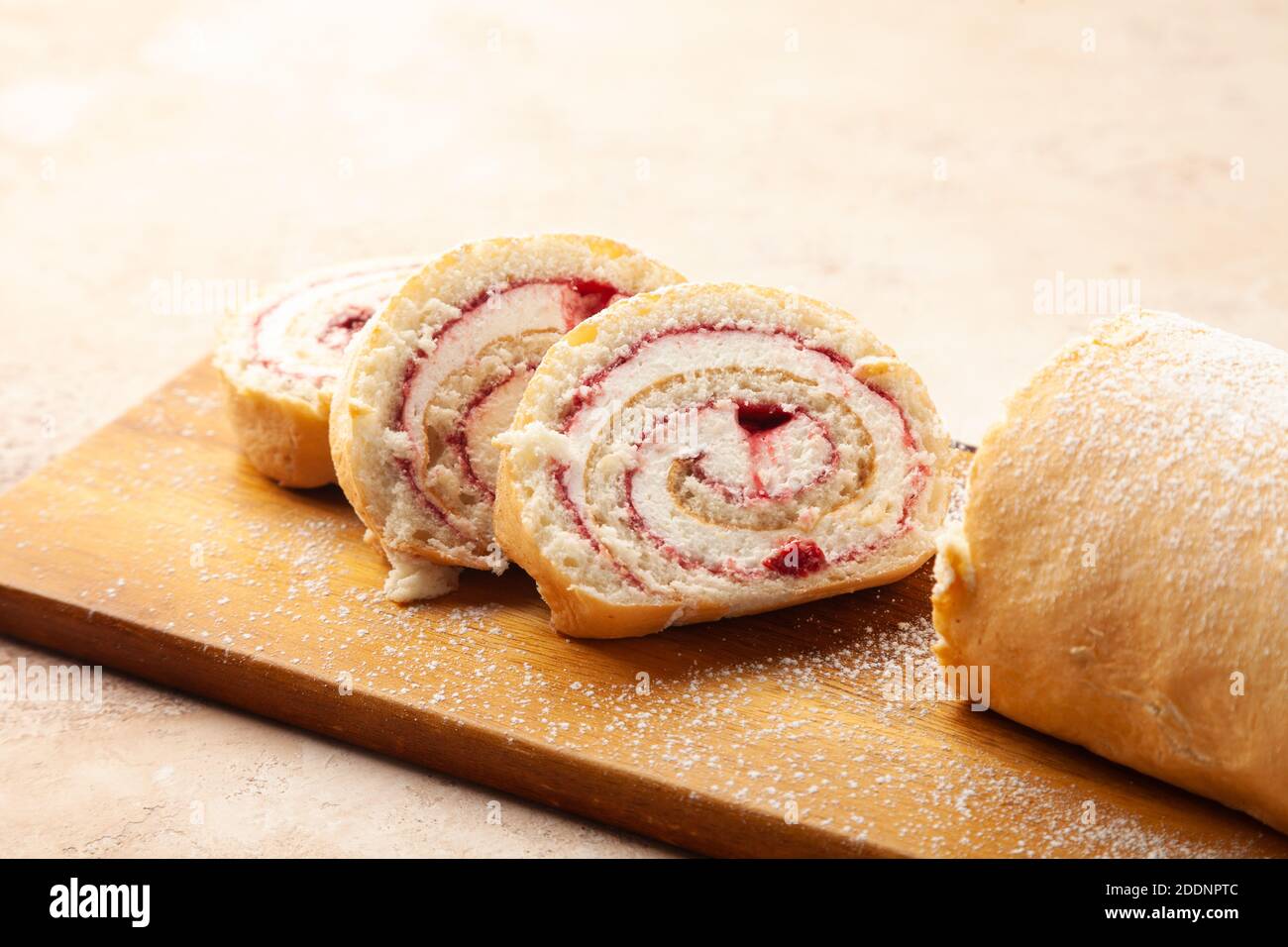 Baked biscuit swiss roll dessert with fruits and cream chopped on ...