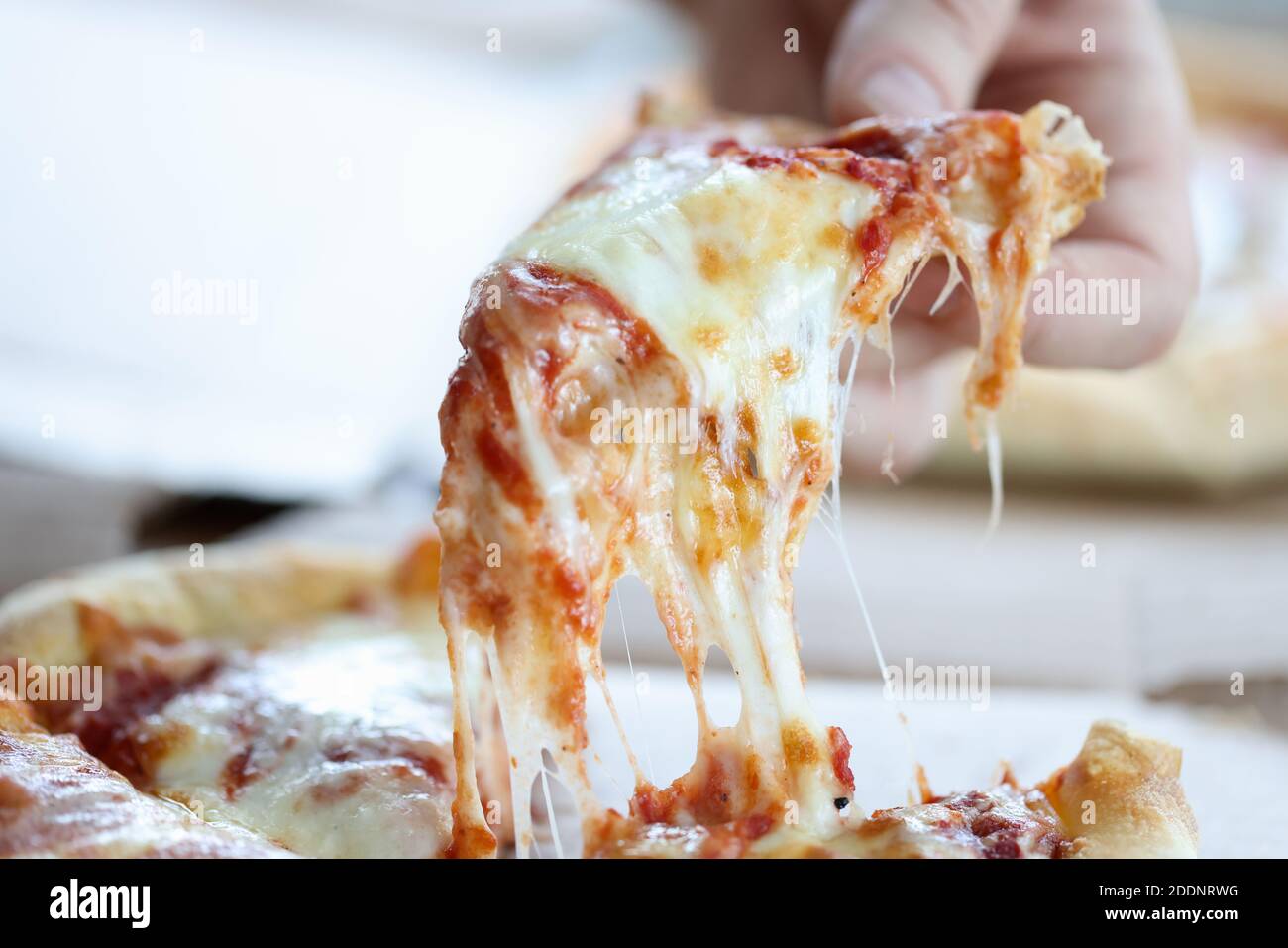 Male hand tearing off slice of pizza for lunch closeup Stock Photo - Alamy