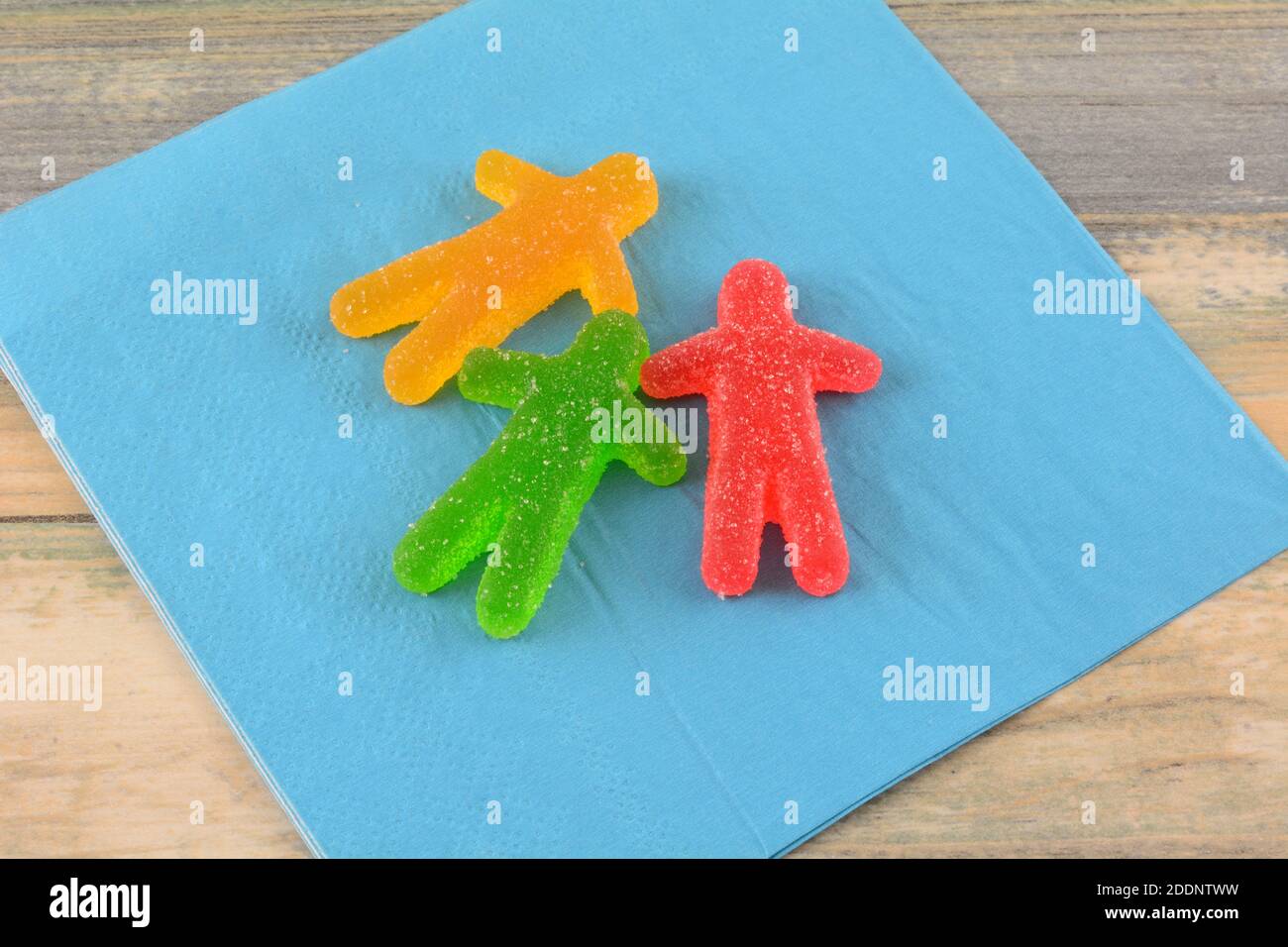 Three fruit chew gummy candy in shape of human on blue napkin on table ...
