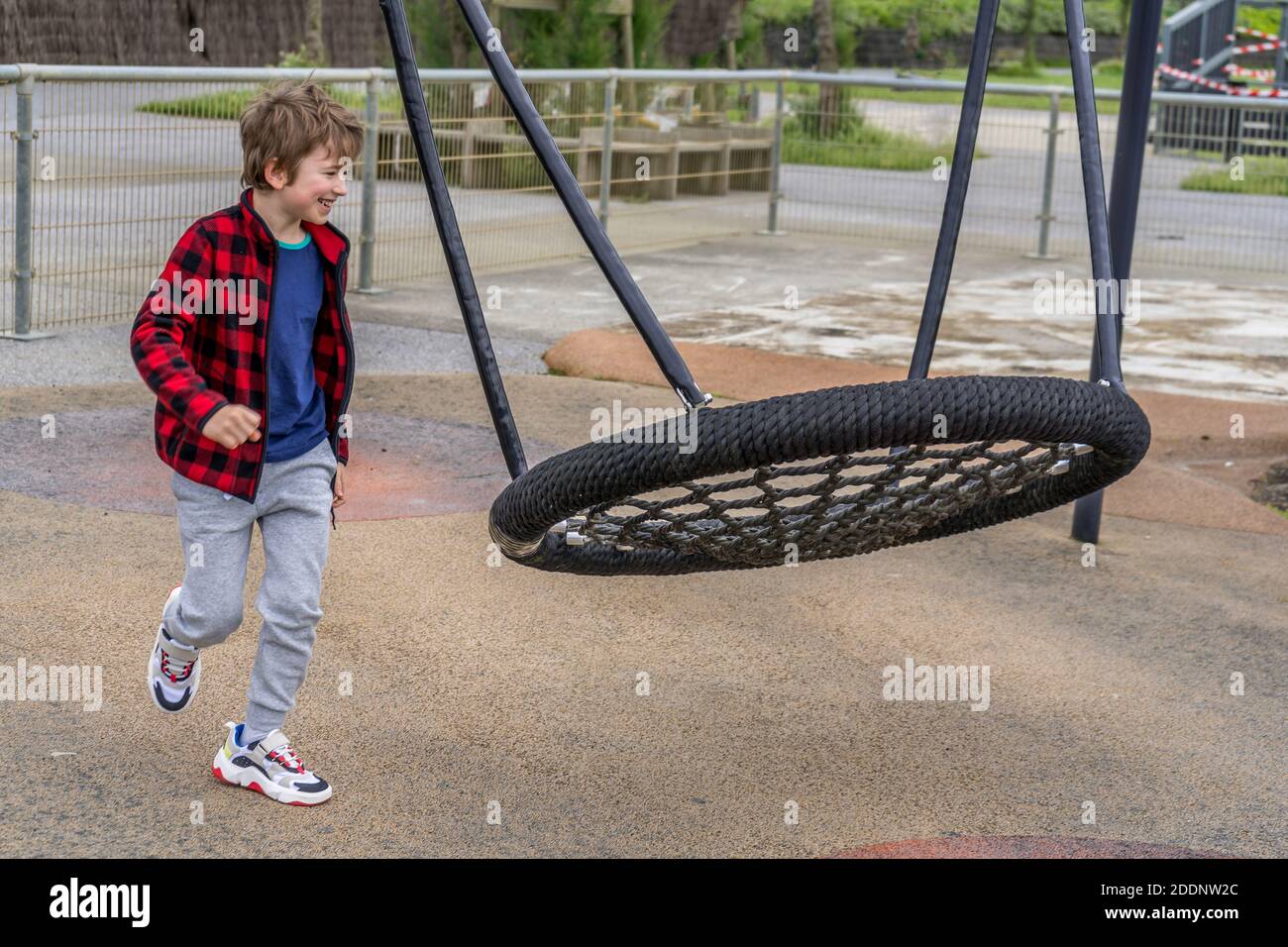 Happy boy playing with swing cobwebs in the playground. Children ...