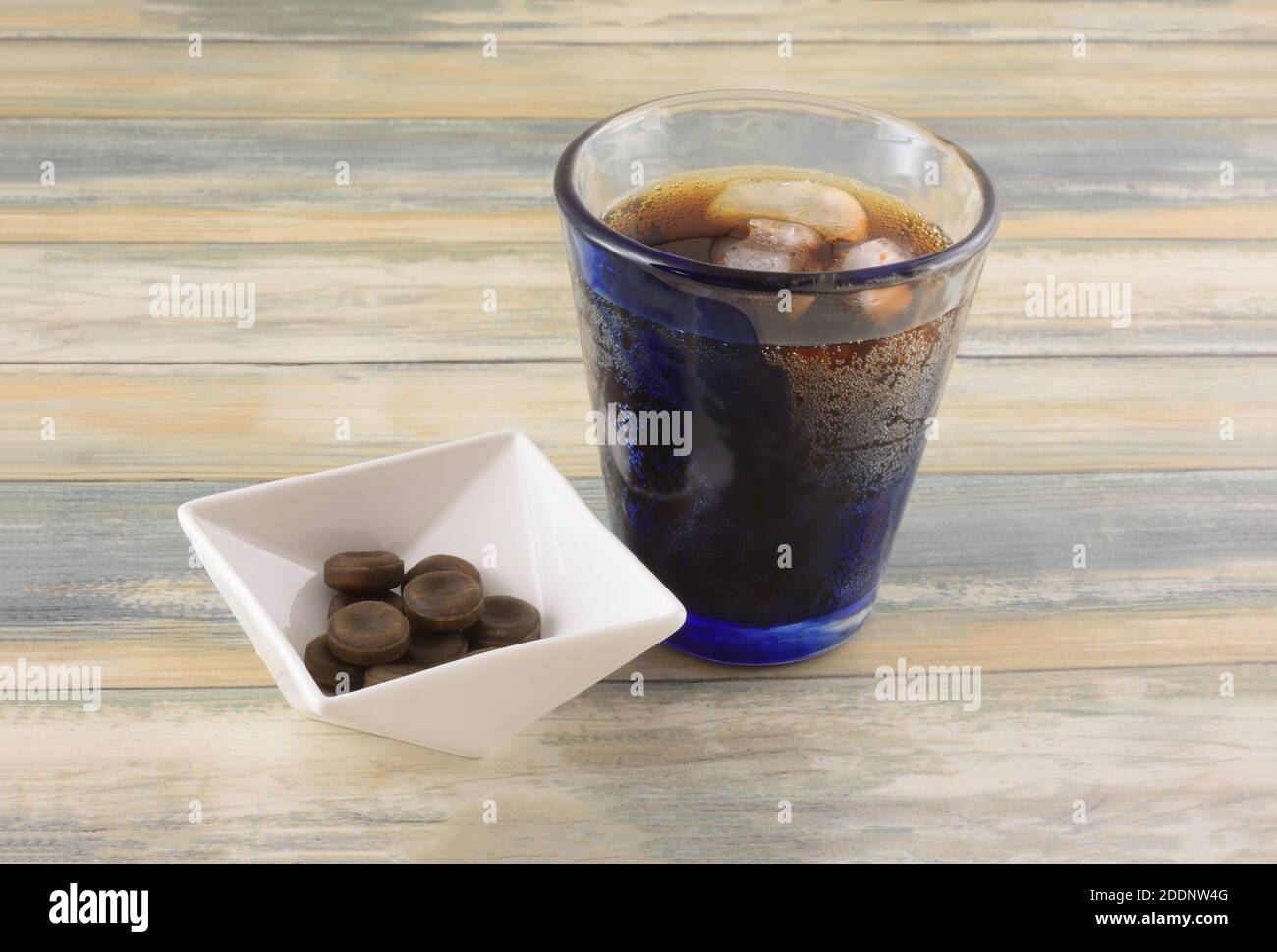 Cola hard candy in white candy dish with cold glass of cola with ice ...
