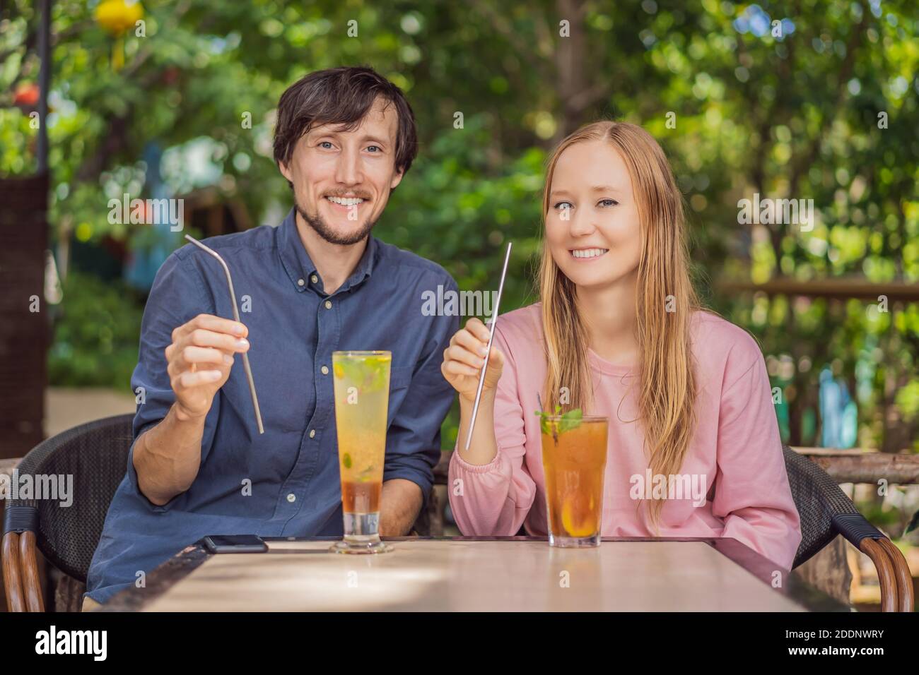 Eco friendly couple using reusable stainless steel straw to drink fruit ...