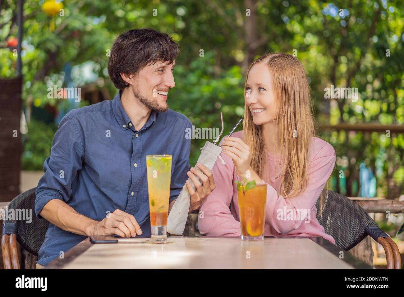 Eco friendly couple using reusable stainless steel straw to drink fruit ...