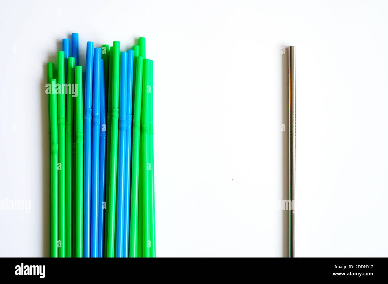 a pile of disposable plastic drinking straws and one reusable stainless ...