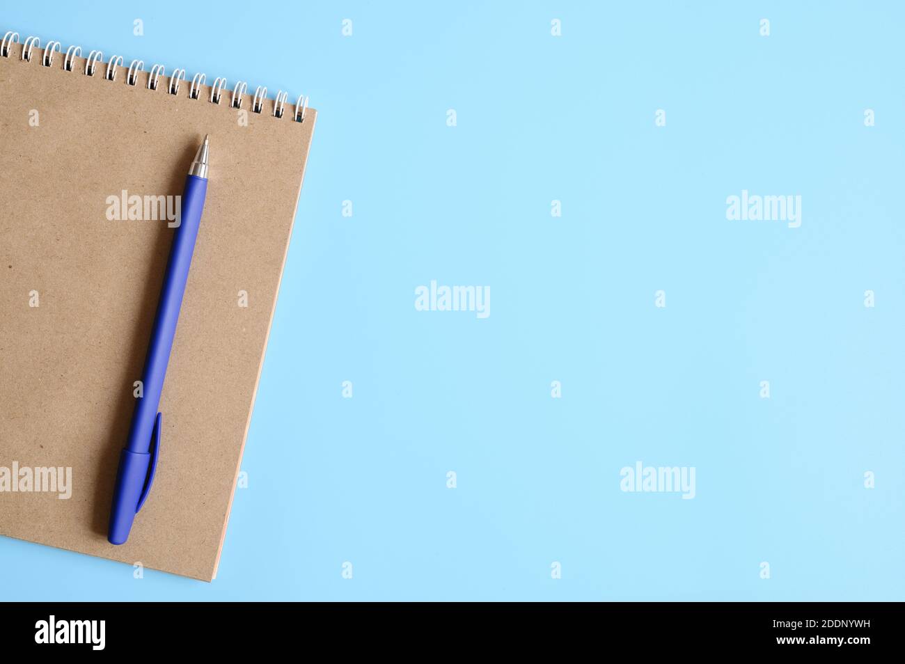 notebook or sketchbook made of craft paper and a pen on a blue ...