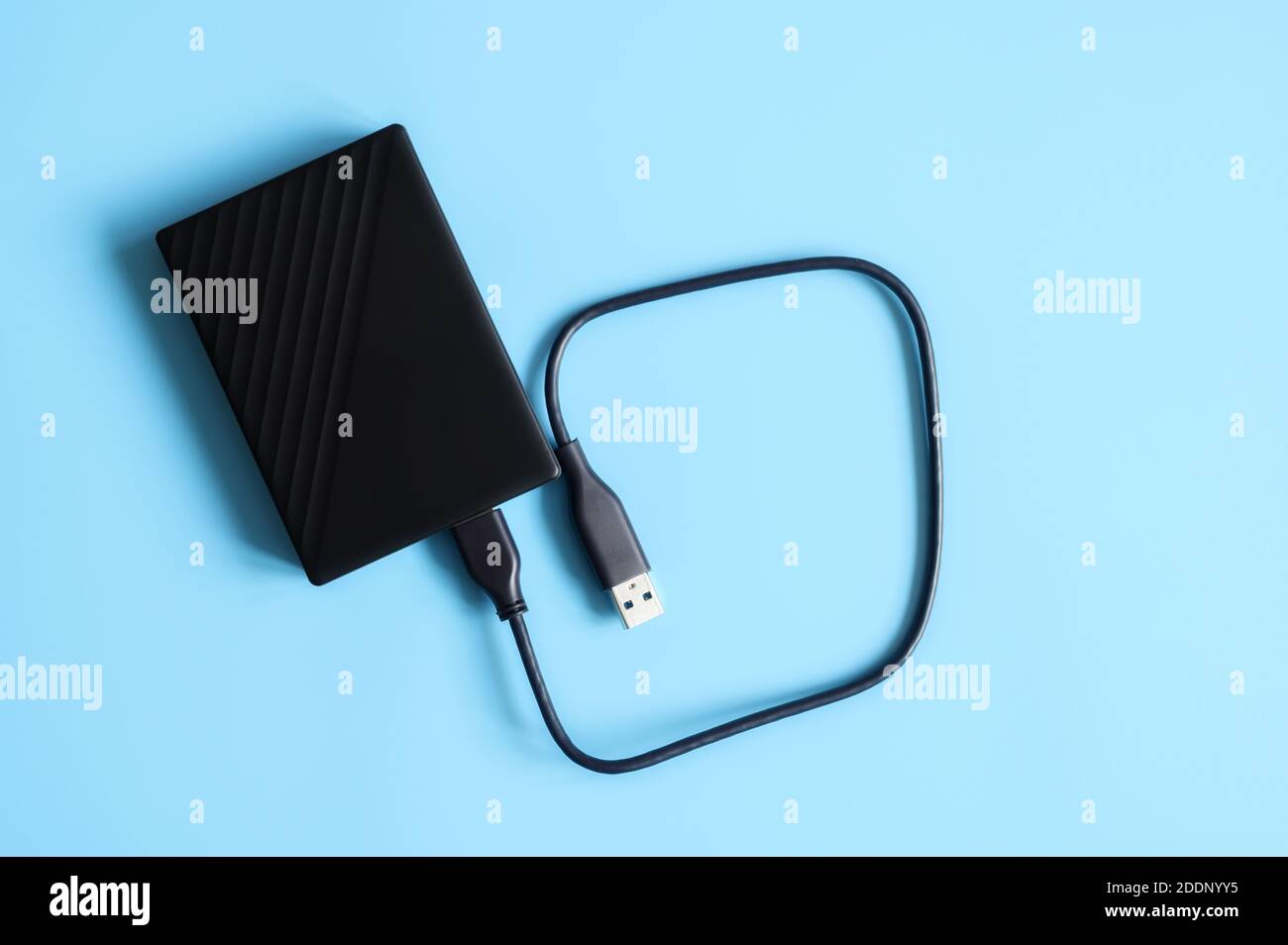 external hard drive black color with connection cable on blue ...