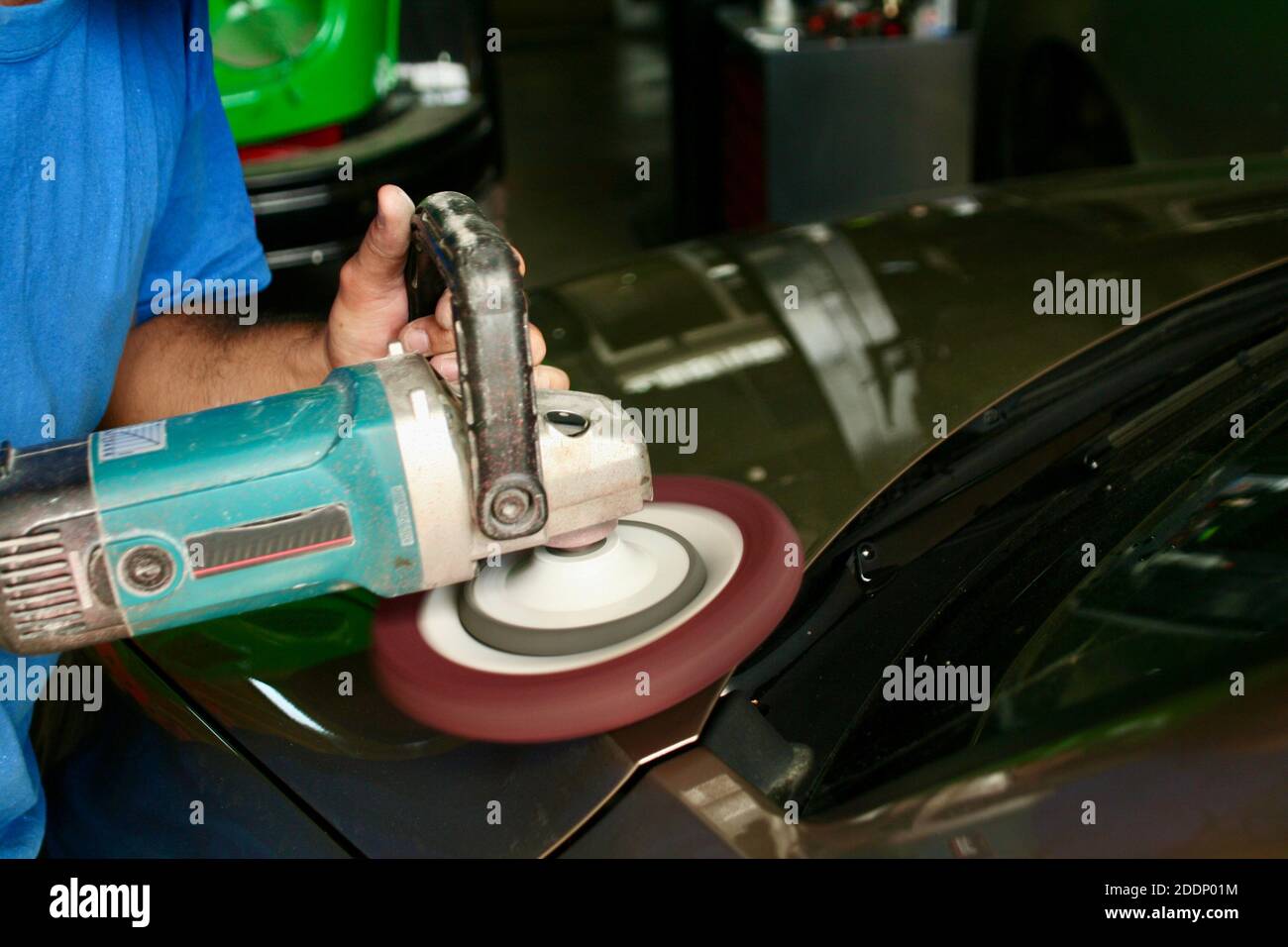 Man polishing front hood of car by burnishing machine. Automobile paint ...