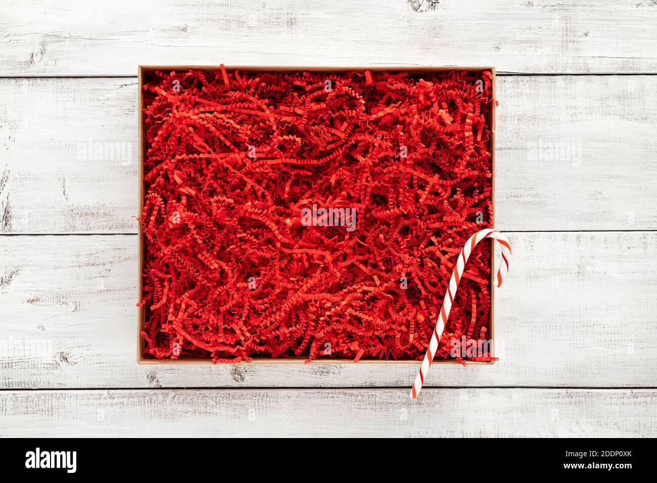 Opened gift box with red shredded paper on white wooden background ...