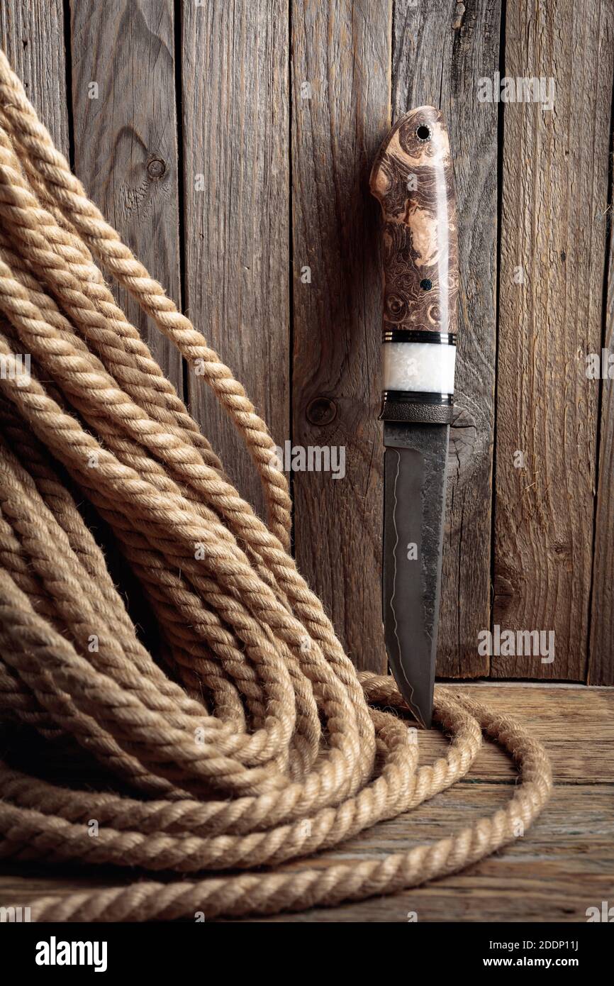 Hunter combat hand made knife and hemp rope on wooden background. The ...