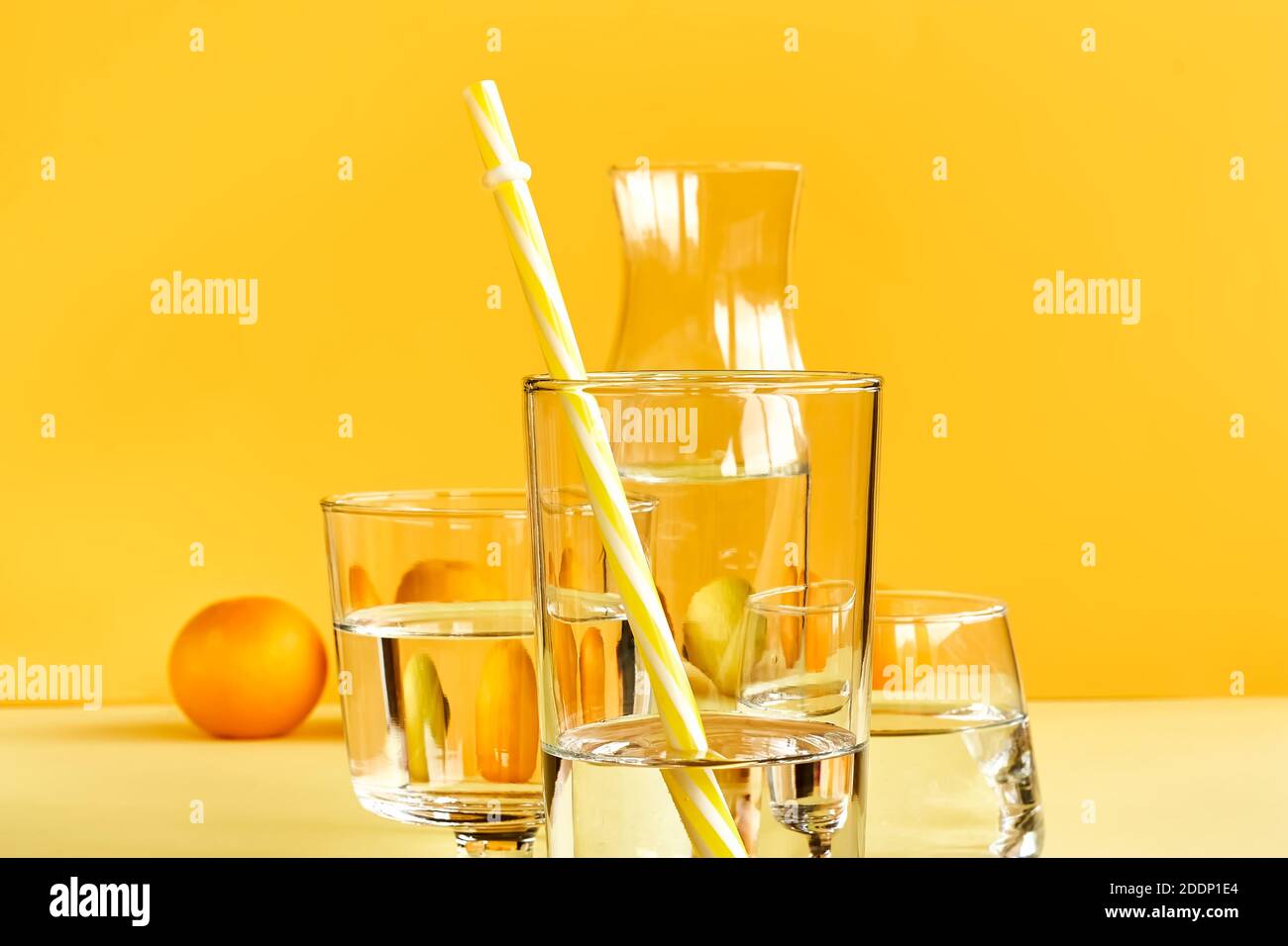 Citrus fruits distorted through water and glass on yellow background ...
