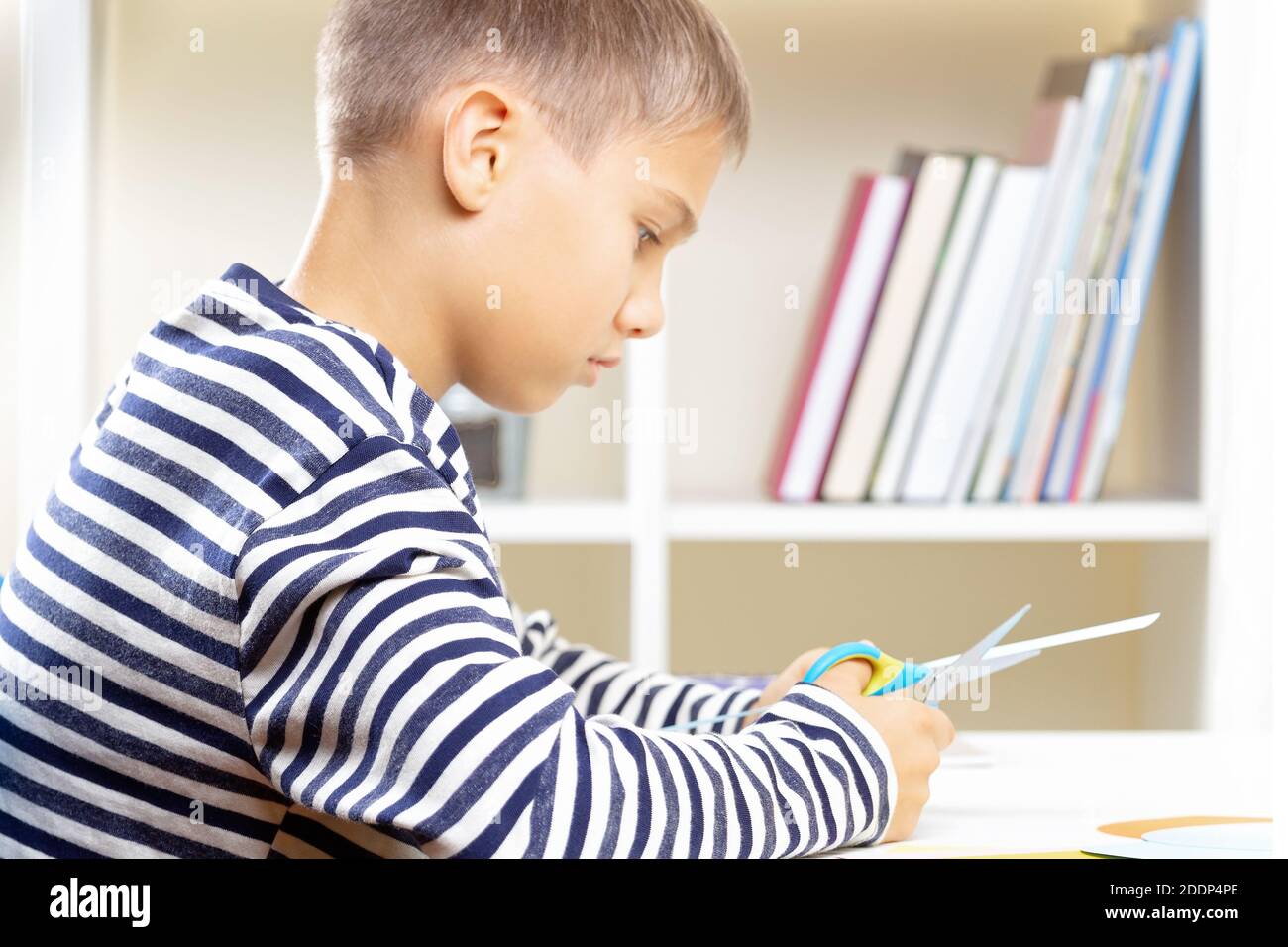 Education, learning, paper craft, entertainment. Boy cutting colored ...