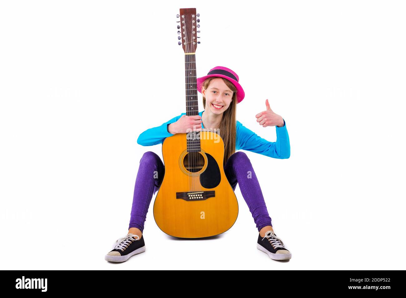 A girl kid holding guitar shows thumb up on a white background in the ...